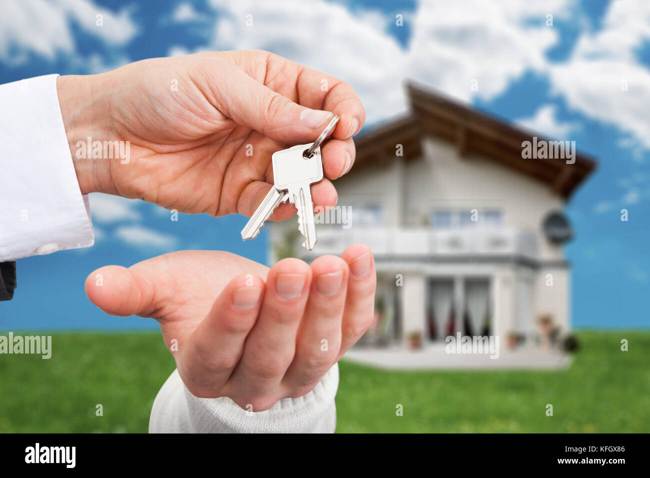 Cropped image of real estate agent giving keys to owner against new ...