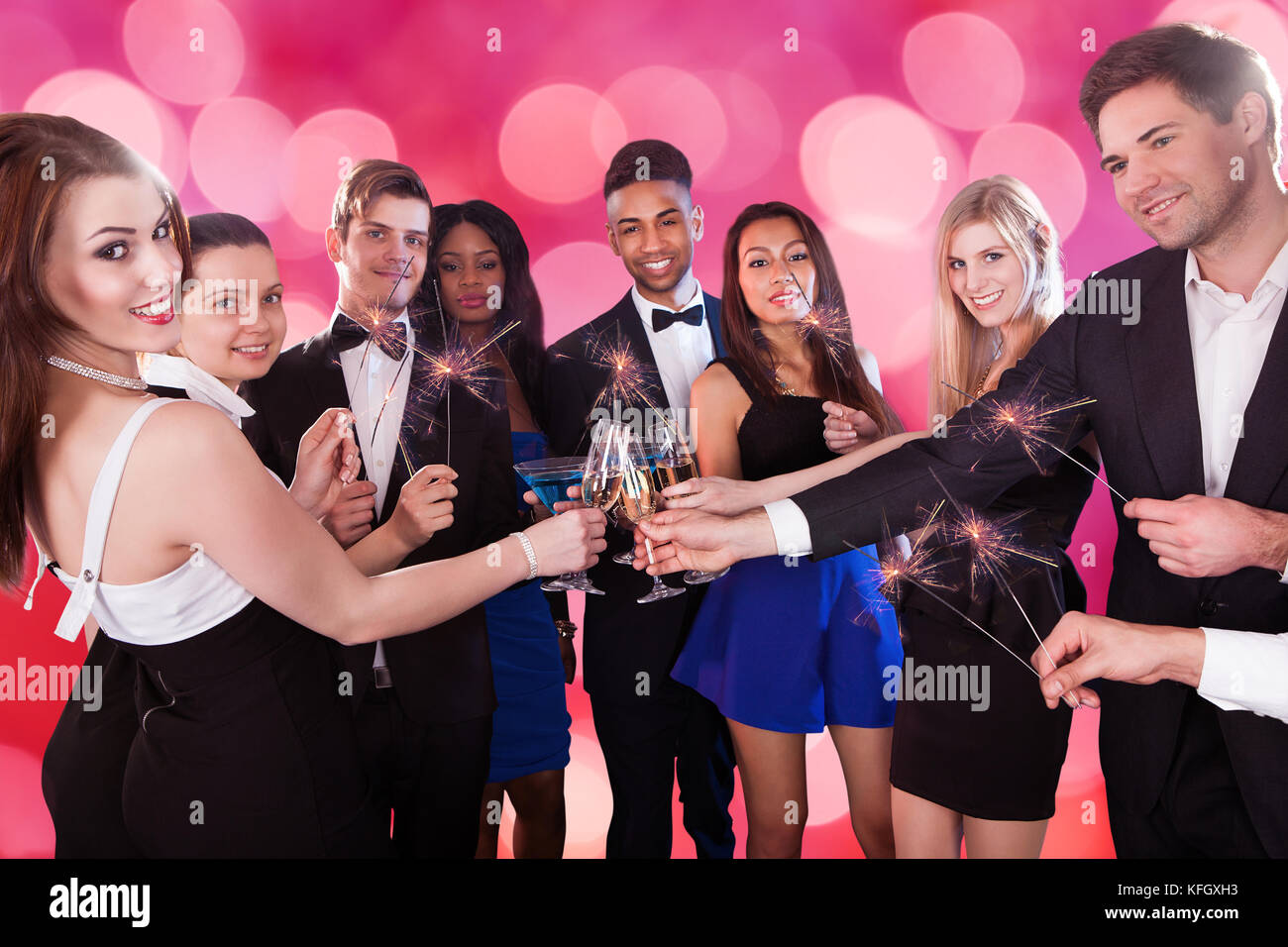 Group portrait of multiethnic friends holding sparklers while toasting ...
