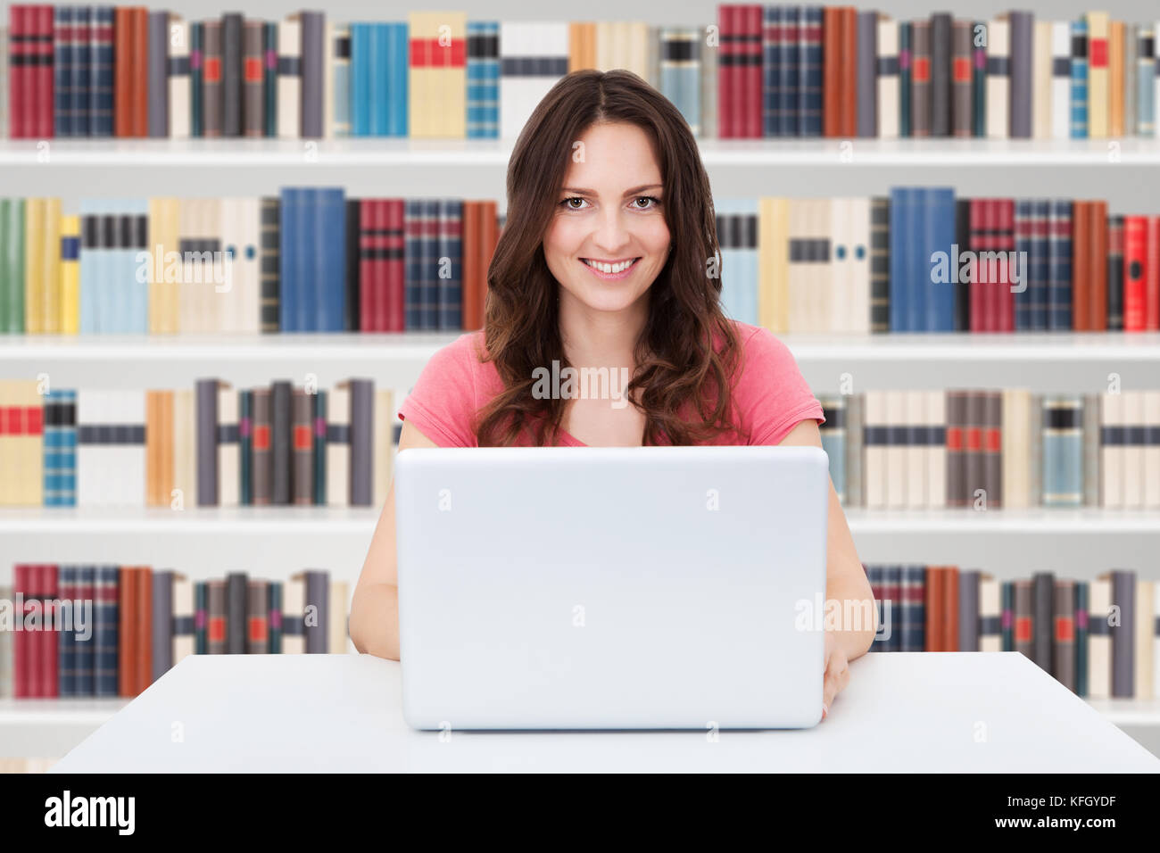 Happy Young Female Student In A Library With Books In Front Of Book ...