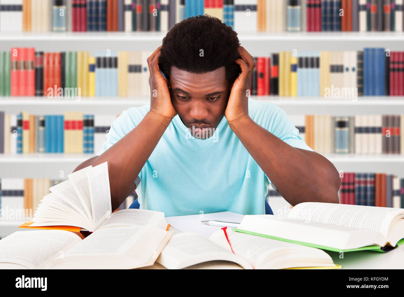 Worried African Student Looking At Books On Desk In Library Stock Photo ...