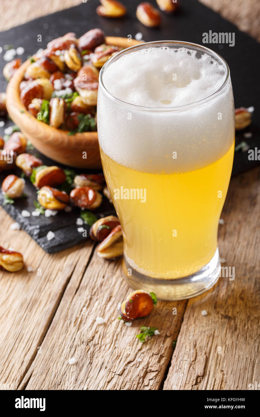 Light beer frothy and fried salted broad beans close-up on the table ...