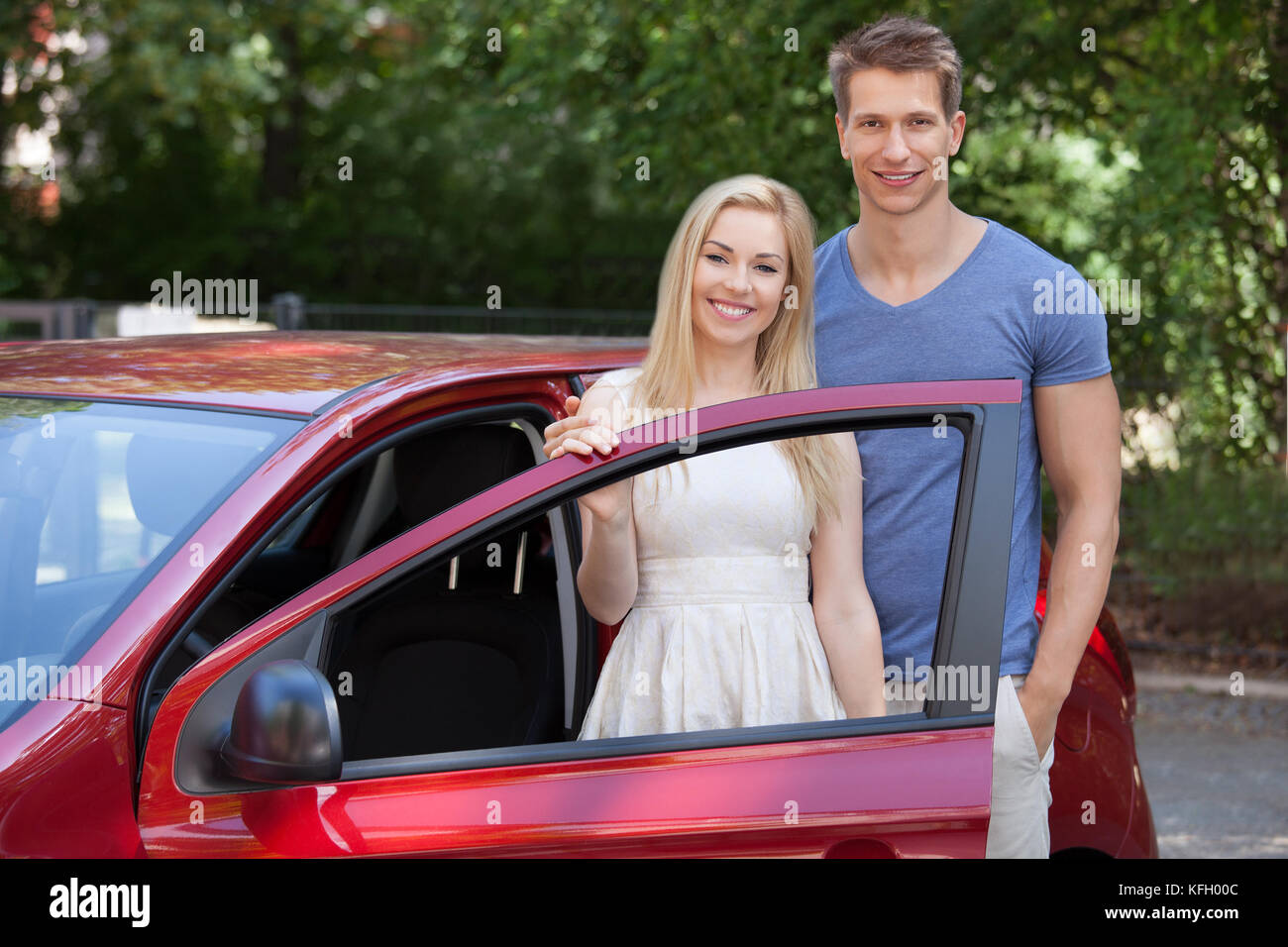 Portrait of happy young couple standing by new car door Stock Photo - Alamy