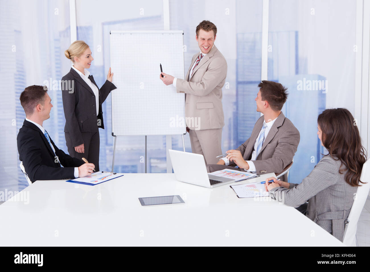 Young businessman giving presentation to colleagues in conference room ...