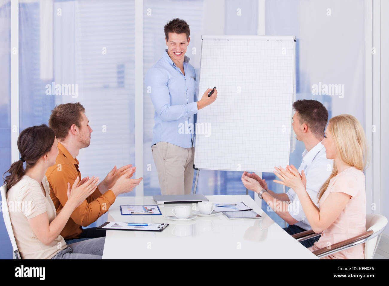 Young business people clapping for male colleague after presentation in ...