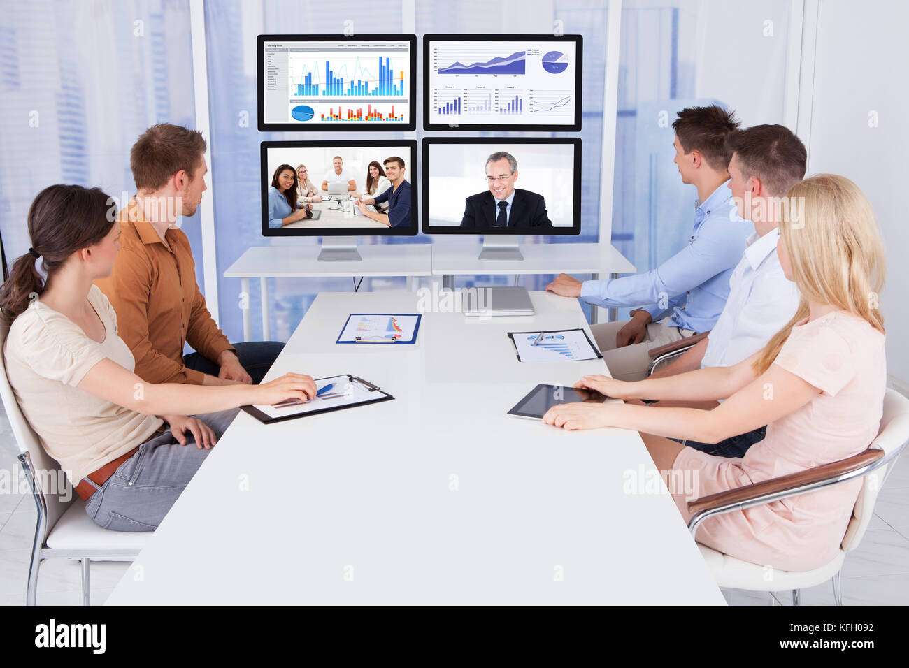Young business people looking at computer monitors in conference room ...