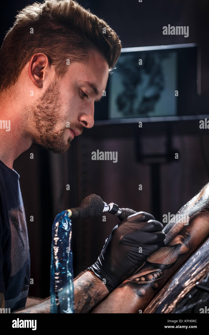 Professional tattoo artist makes a tattoo on a young man's hand Stock ...
