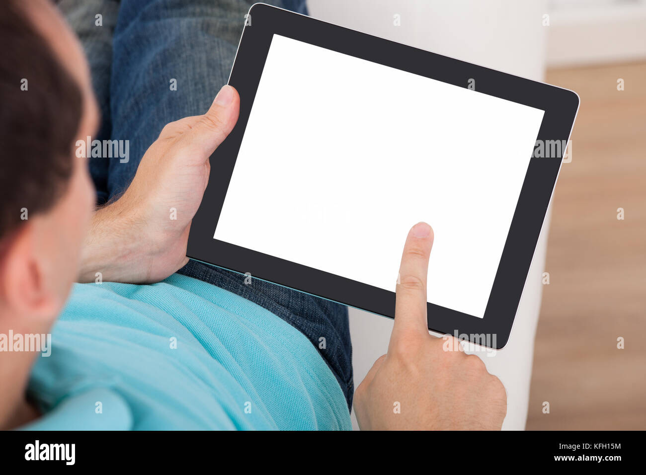 Closeup of mid adult man looking at blank screen of digital tablet at ...