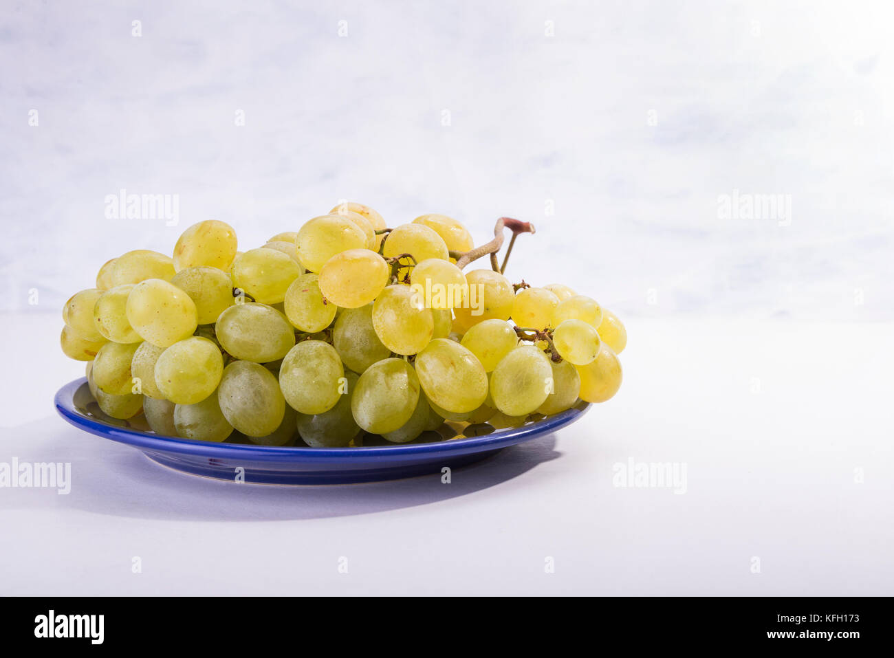 The plate is full of sweet yellow grapes on the white background Stock ...
