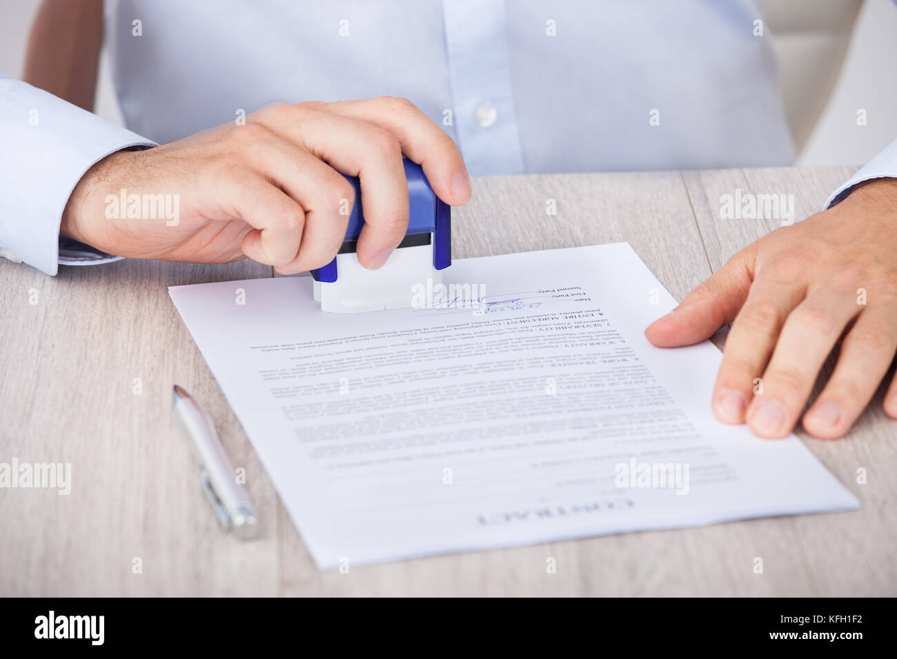 Cropped image of businessman stamping contract paper at desk in office ...