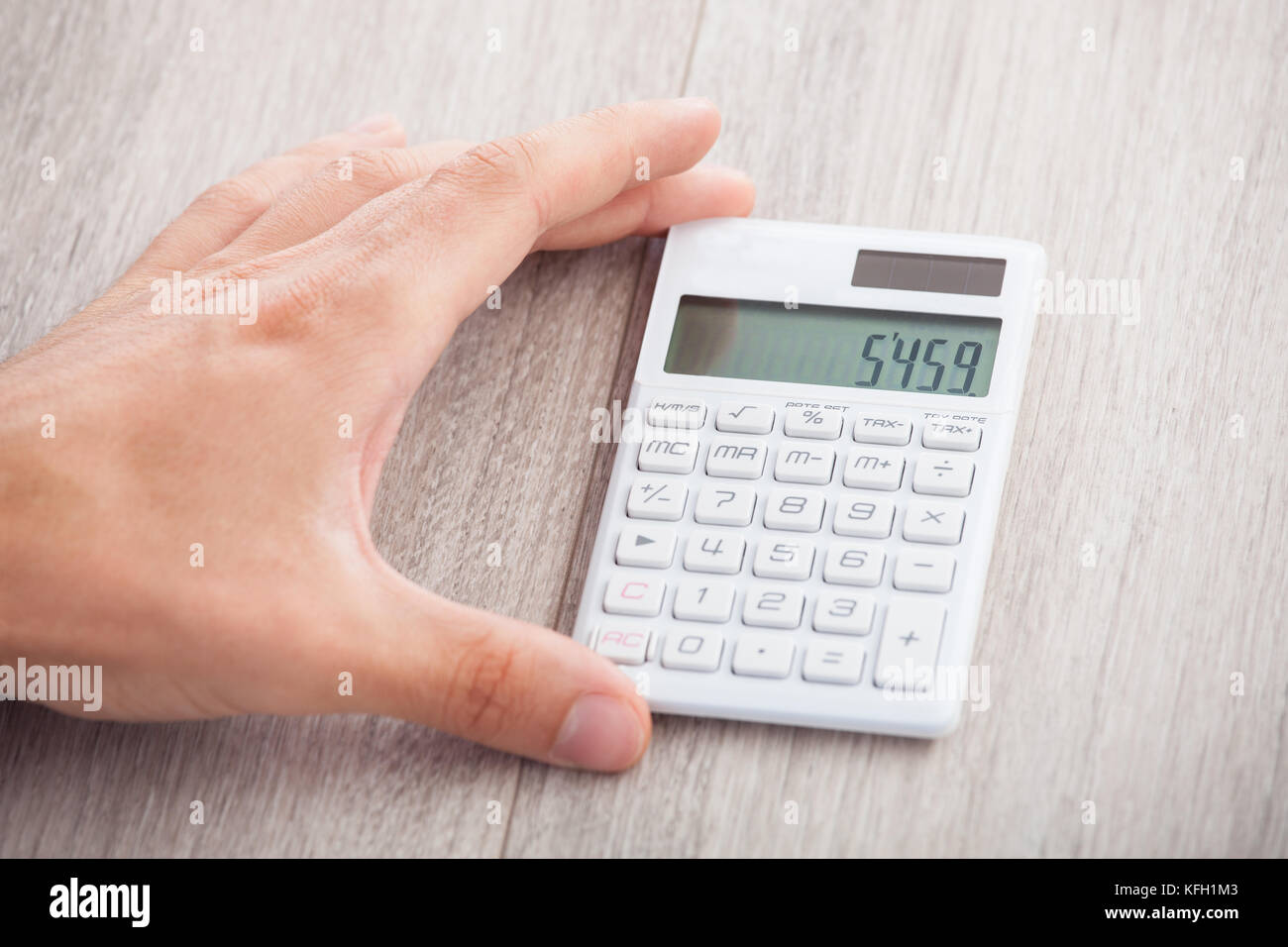 Closeup of businessman's hand holding calculator on desk Stock Photo ...