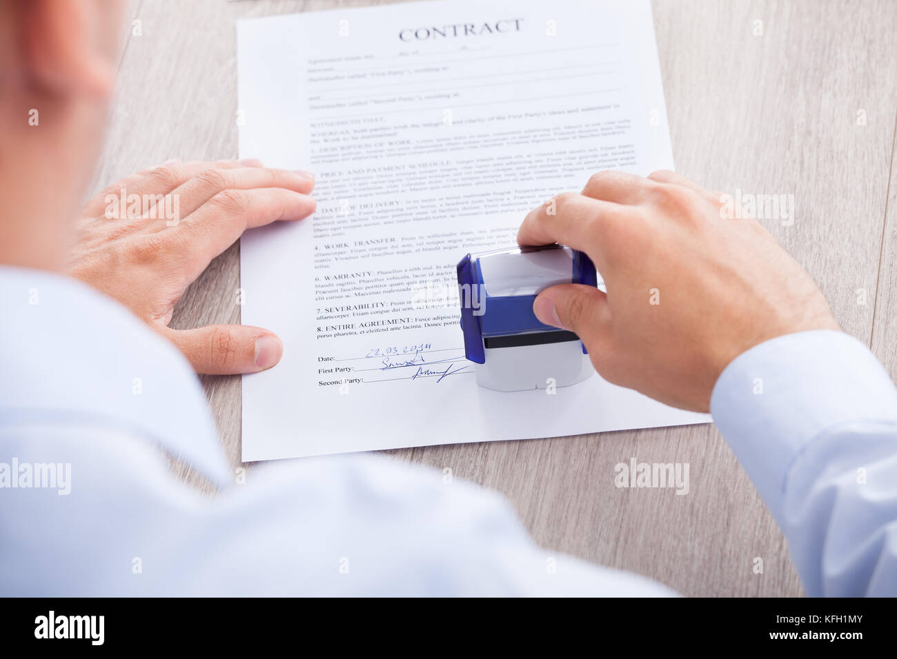Cropped image of businessman stamping contract paper on table Stock ...