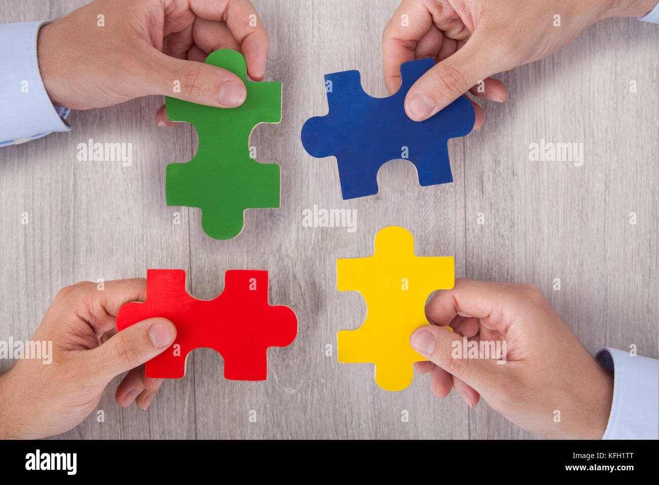 Cropped image of businesspeople joining multicolored puzzle pieces at ...