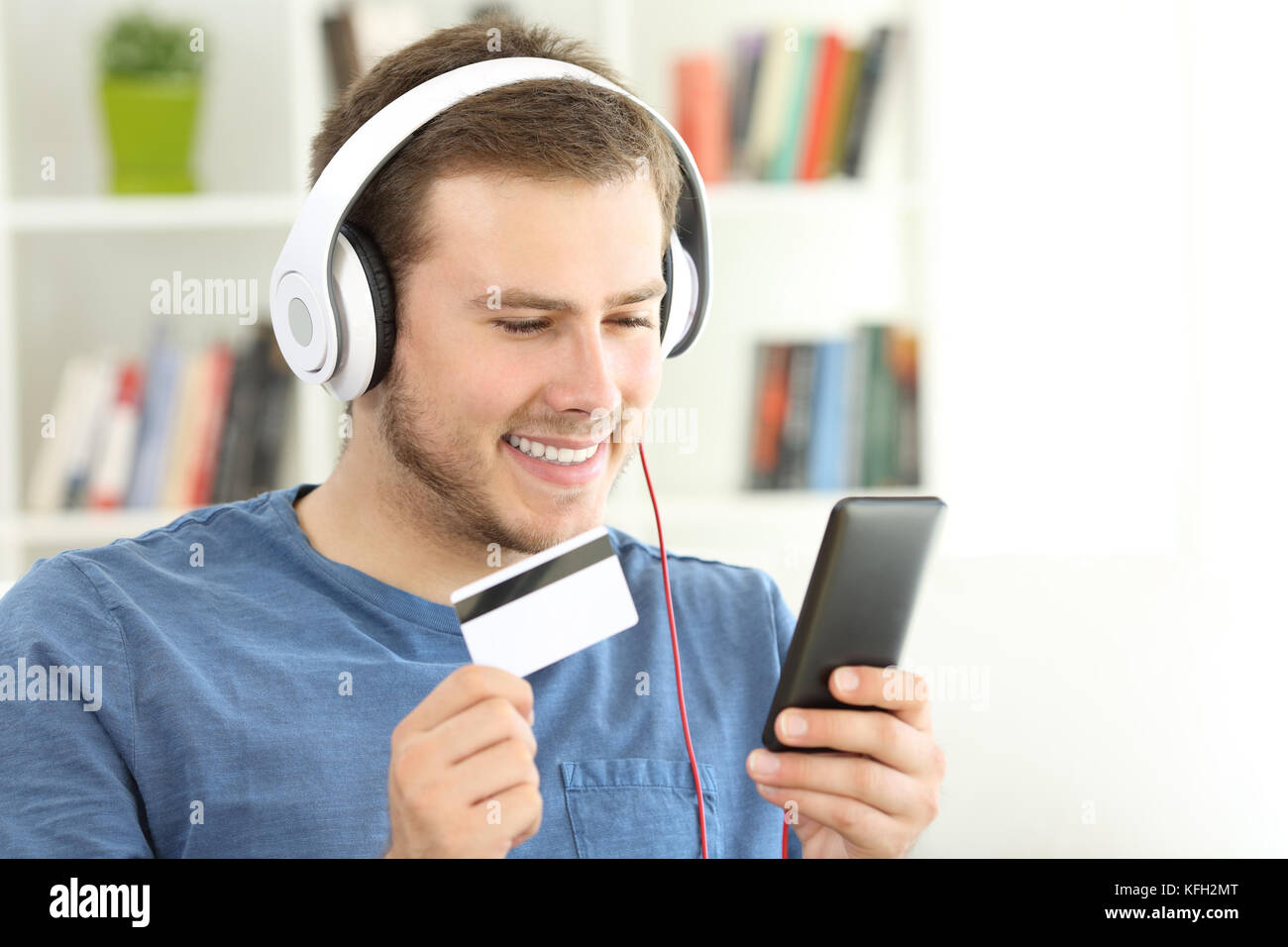 Happy guy wearing headphones paying streaming music with credit card ...