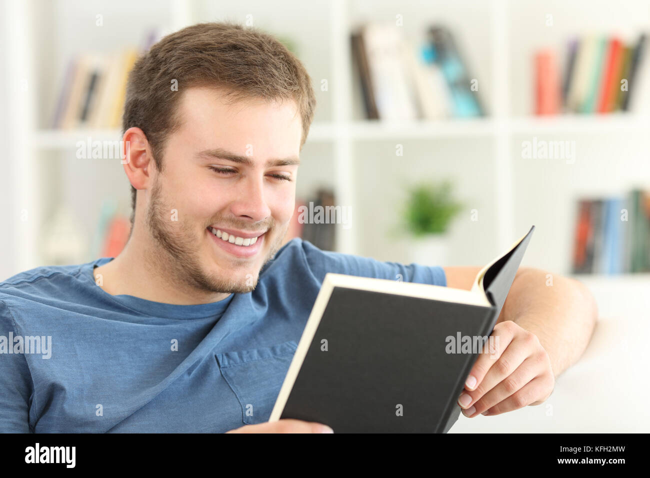 Happy guy reading a paper book sitting on a sofa at home Stock Photo ...