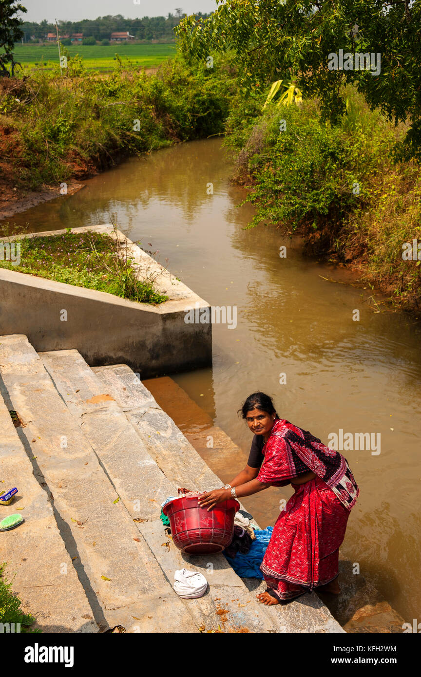 Indian woman washing clothes on a small river in the rural Karnataka ...