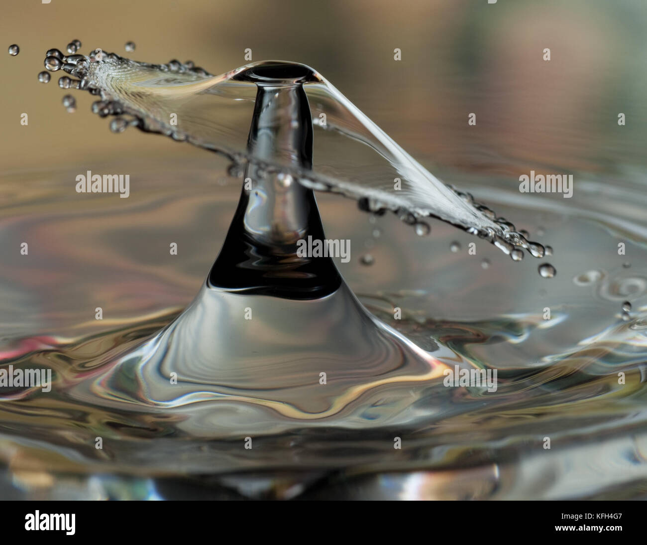 Two drops of water colliding, with second drop striking just as first ...