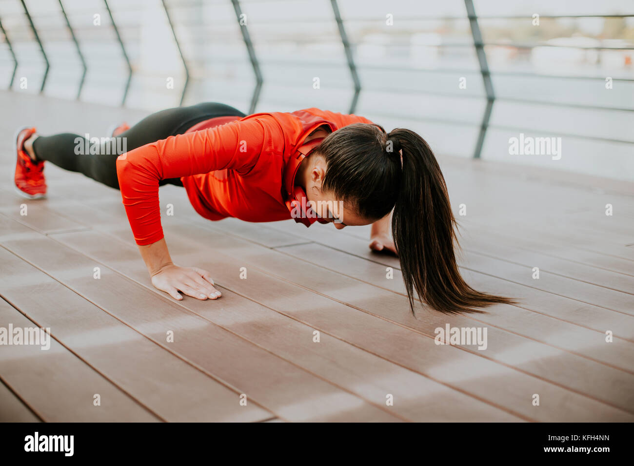 Young woman doing plank exercises on the promenade after running in the ...