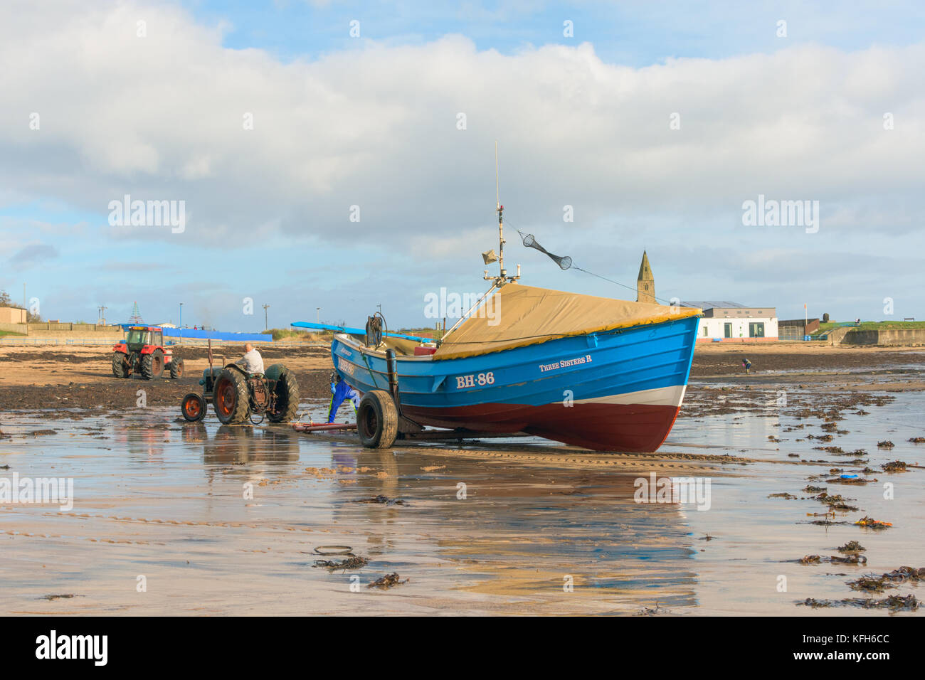 Tradditional Coble fishing boat being hauled out of the sea after a ...