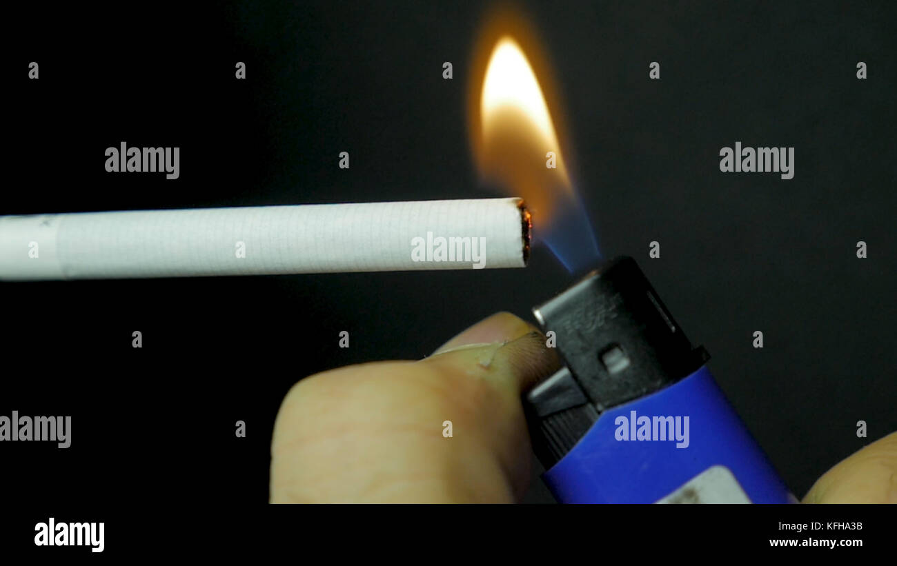 Hand lighting lighter cigarette closeup. Burning cigarette on black ...