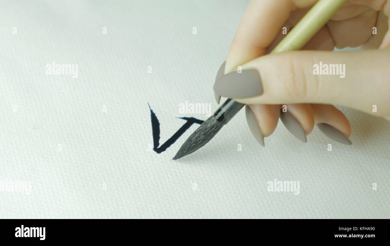 Woman's hands writing Chinese hieroglyph. Female hand holding a writing ...