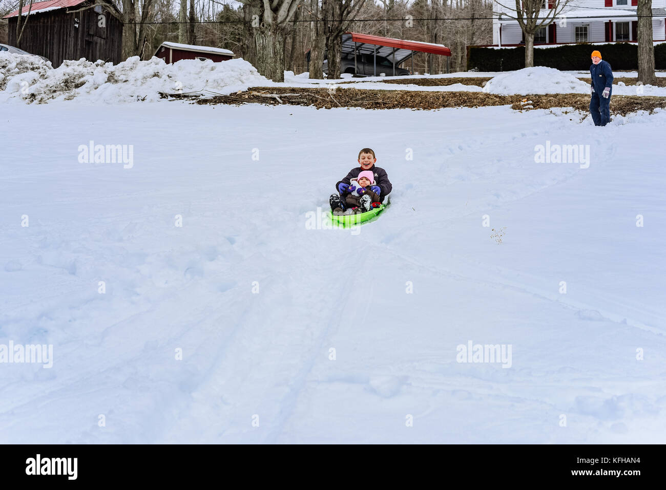 Two children sledding down a snow covered hill Stock Photo - Alamy