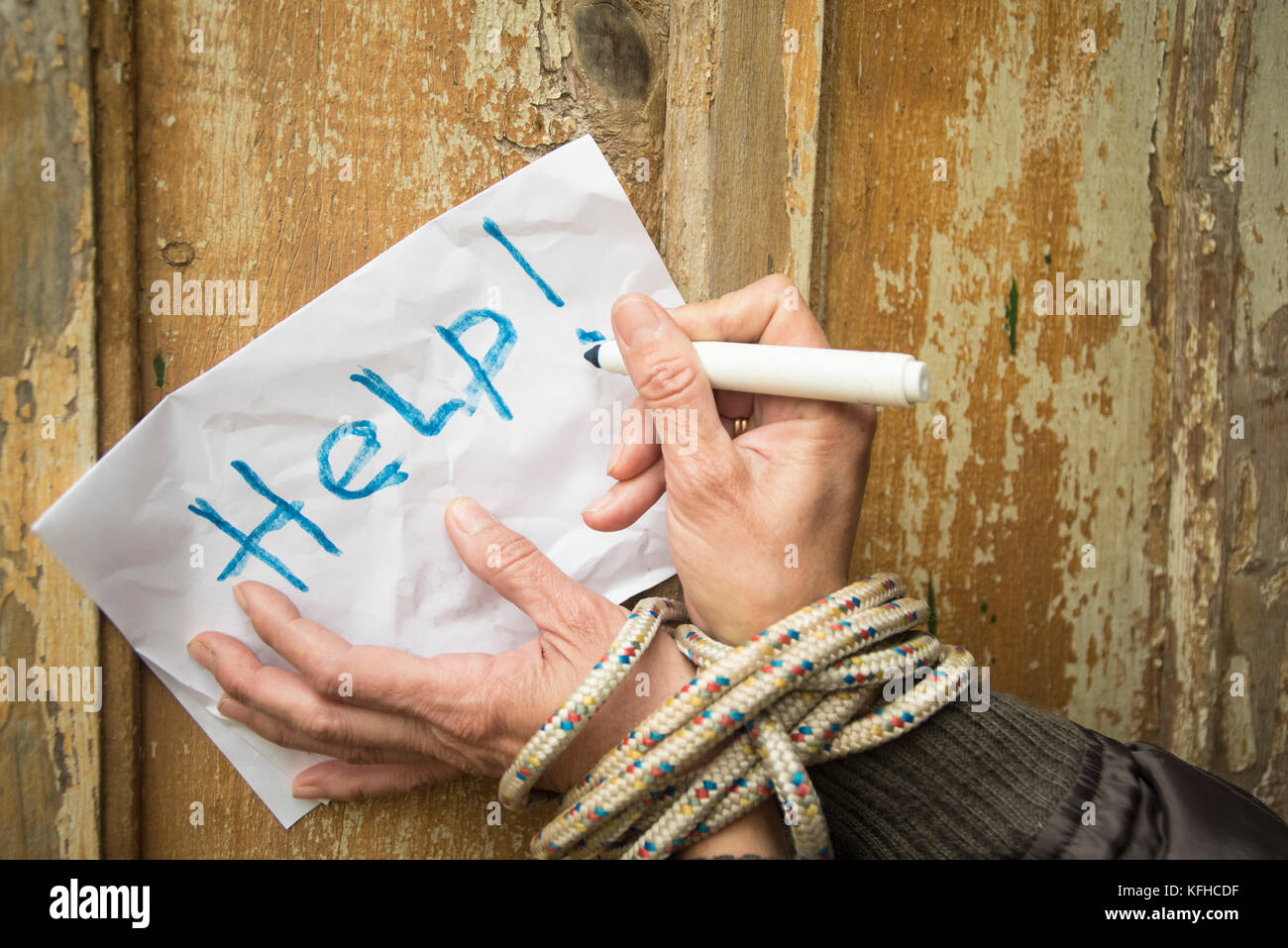 Hands tied with rope writing Help on a piece of paper, shallow depth of ...