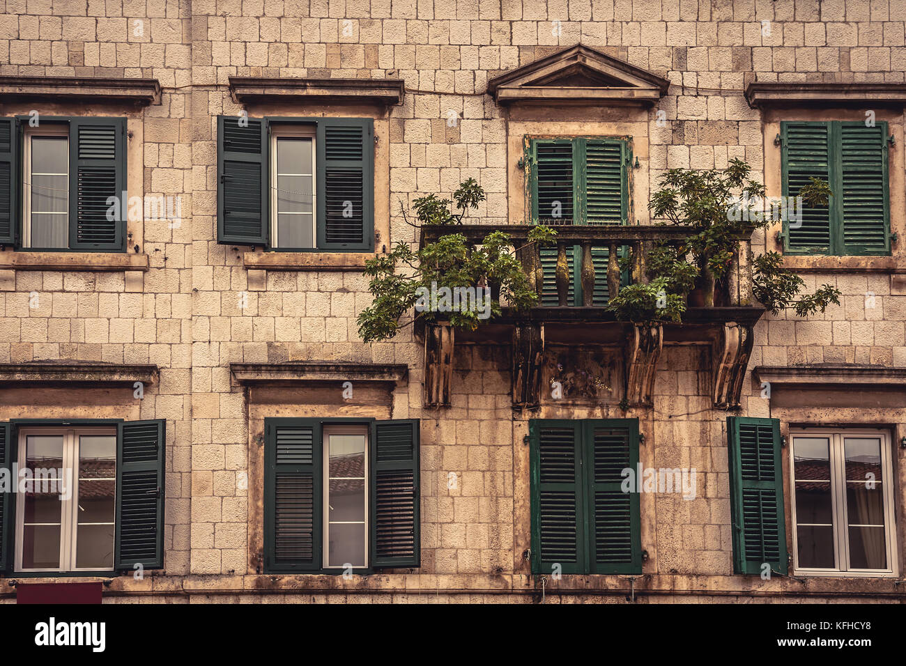 Old balcony with trees and flowers on old medieval building facade with ...