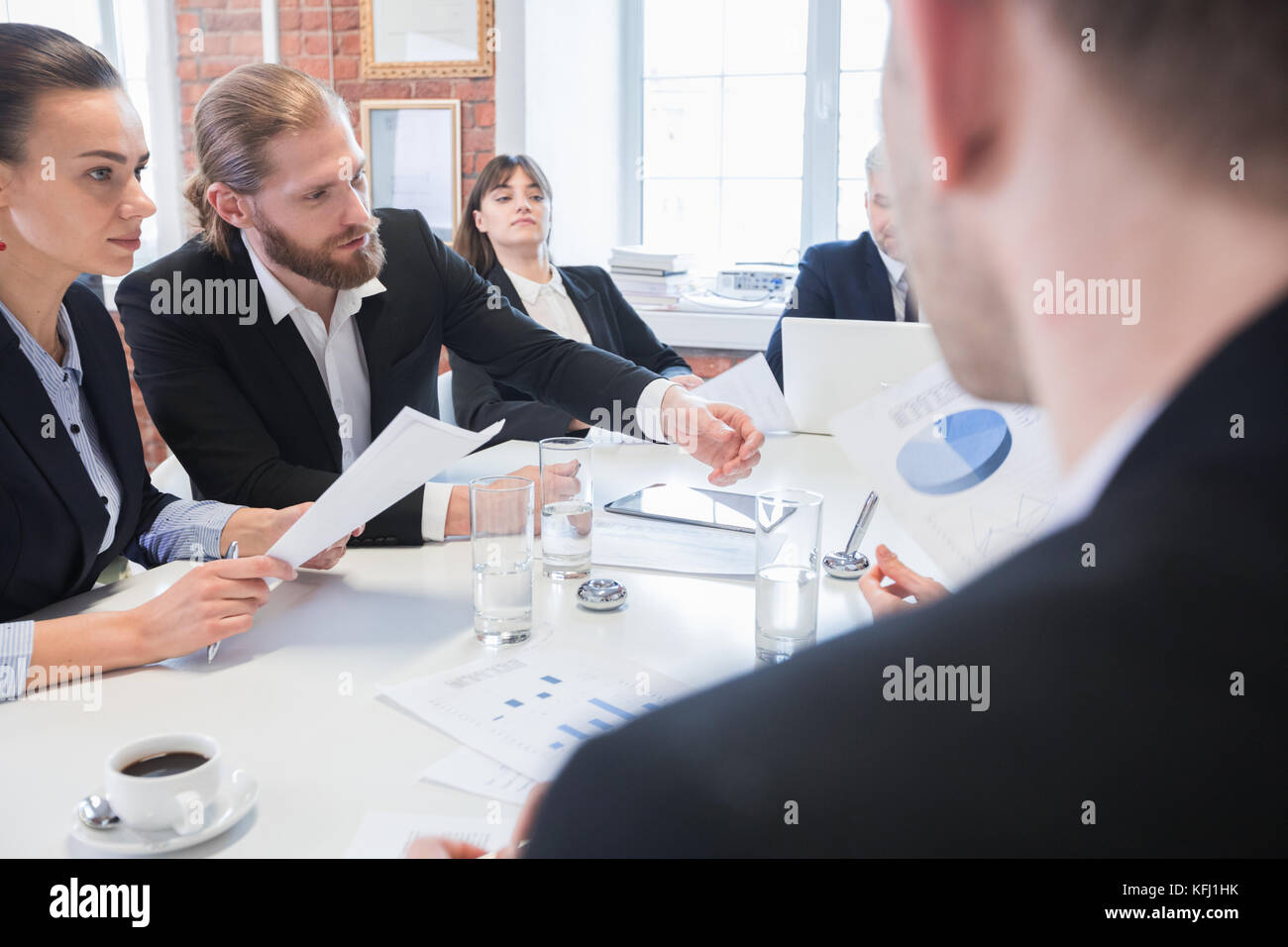 Meeting of business partners talking at the table discussing diagrams ...