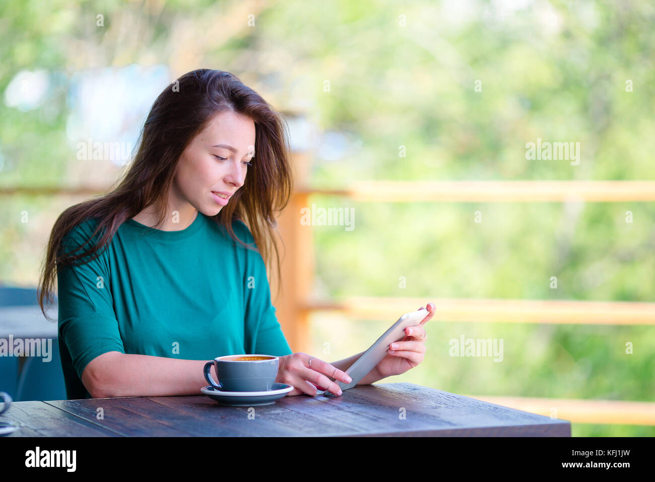 Young charming woman calling with cell telephone while sitting alone in ...