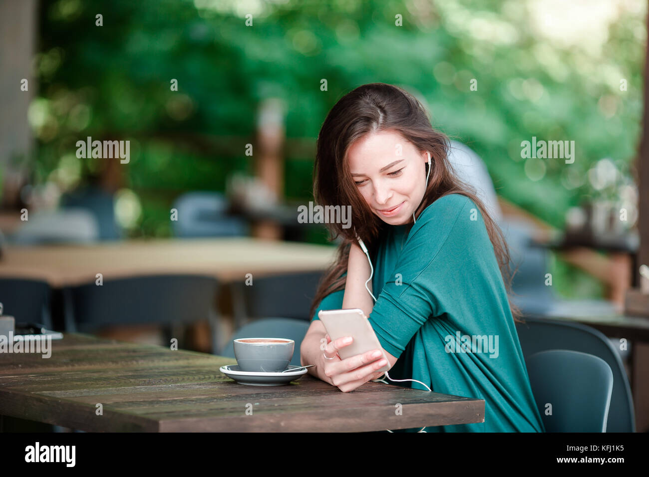 Young charming woman calling with cell telephone while sitting alone in ...