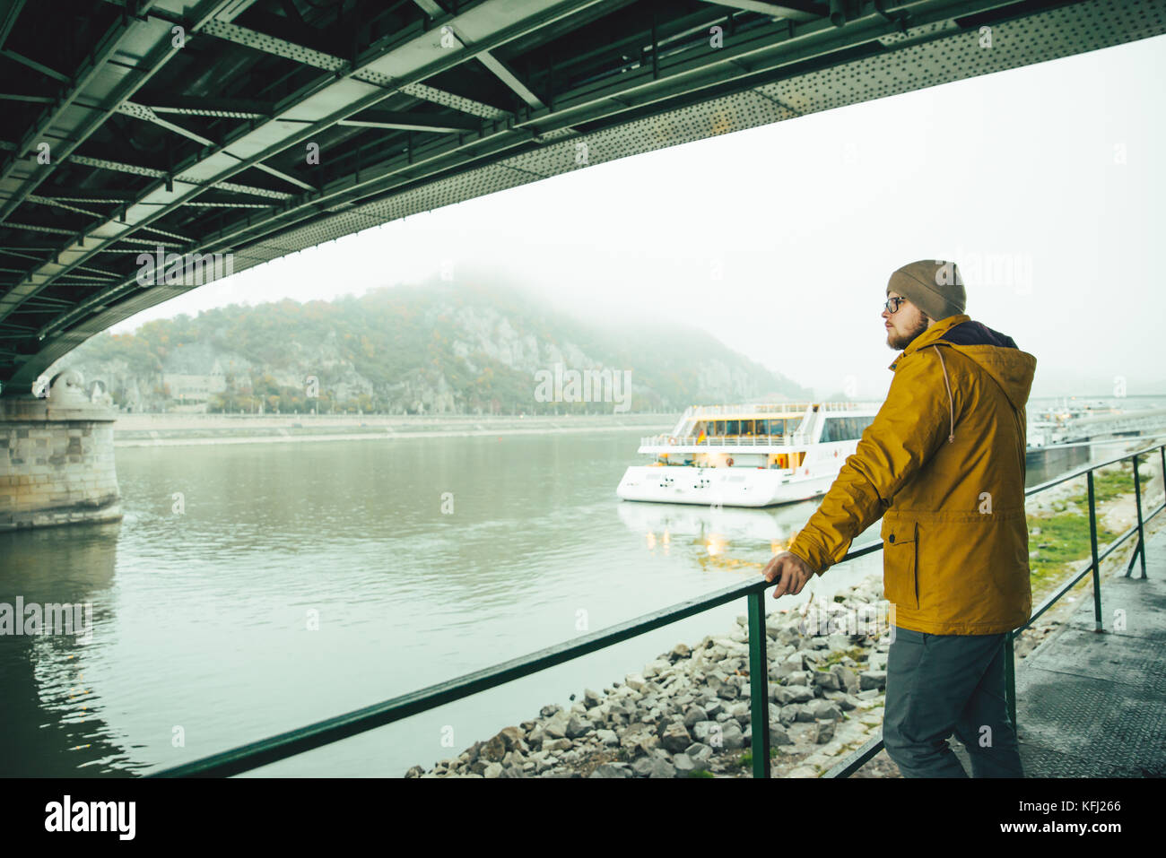 man standing under the bridge boat in the river in the foggy morning ...