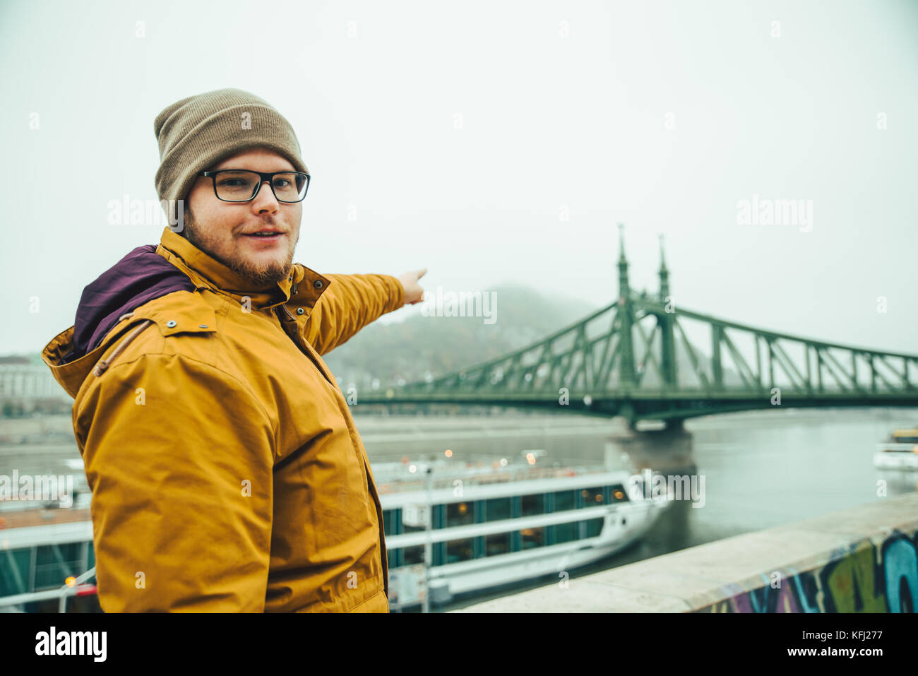 man pointing while standing near river in foggy morning bridge on ...