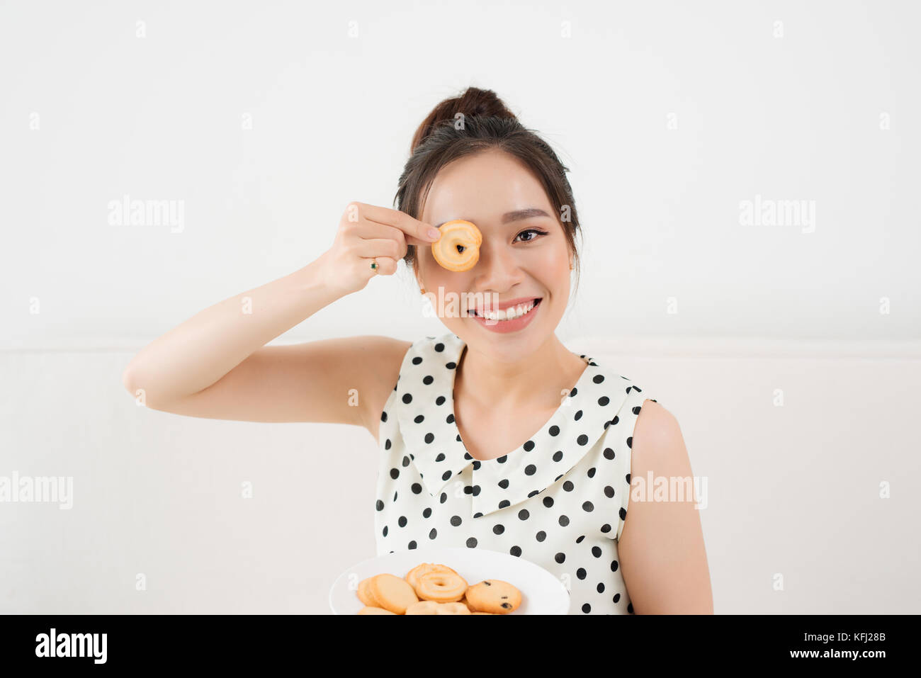 Beautiful woman eating cookies sitting on a couch at home Stock Photo ...