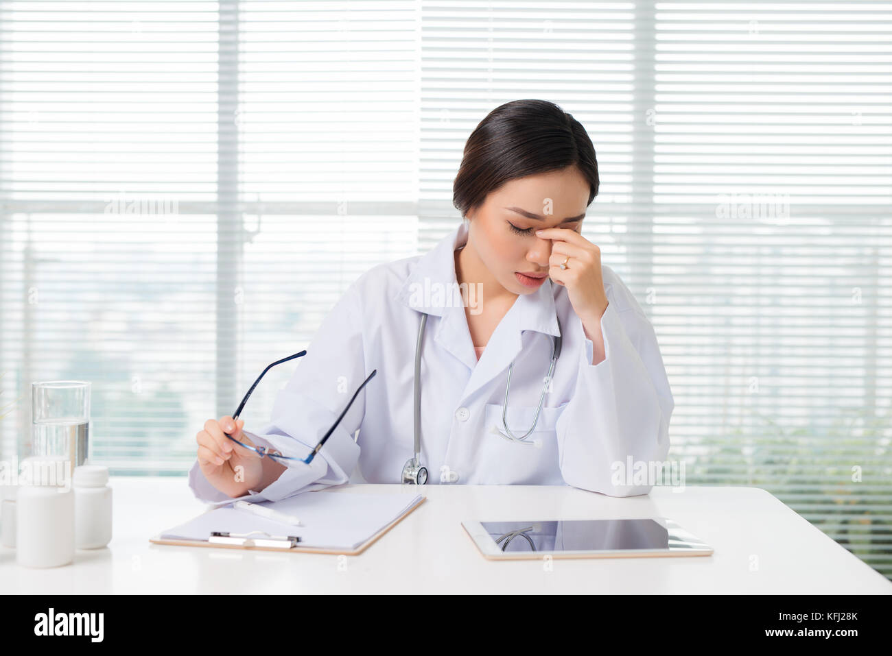 Frustrated young woman doctor keeping eyes closed with coat wearing ...
