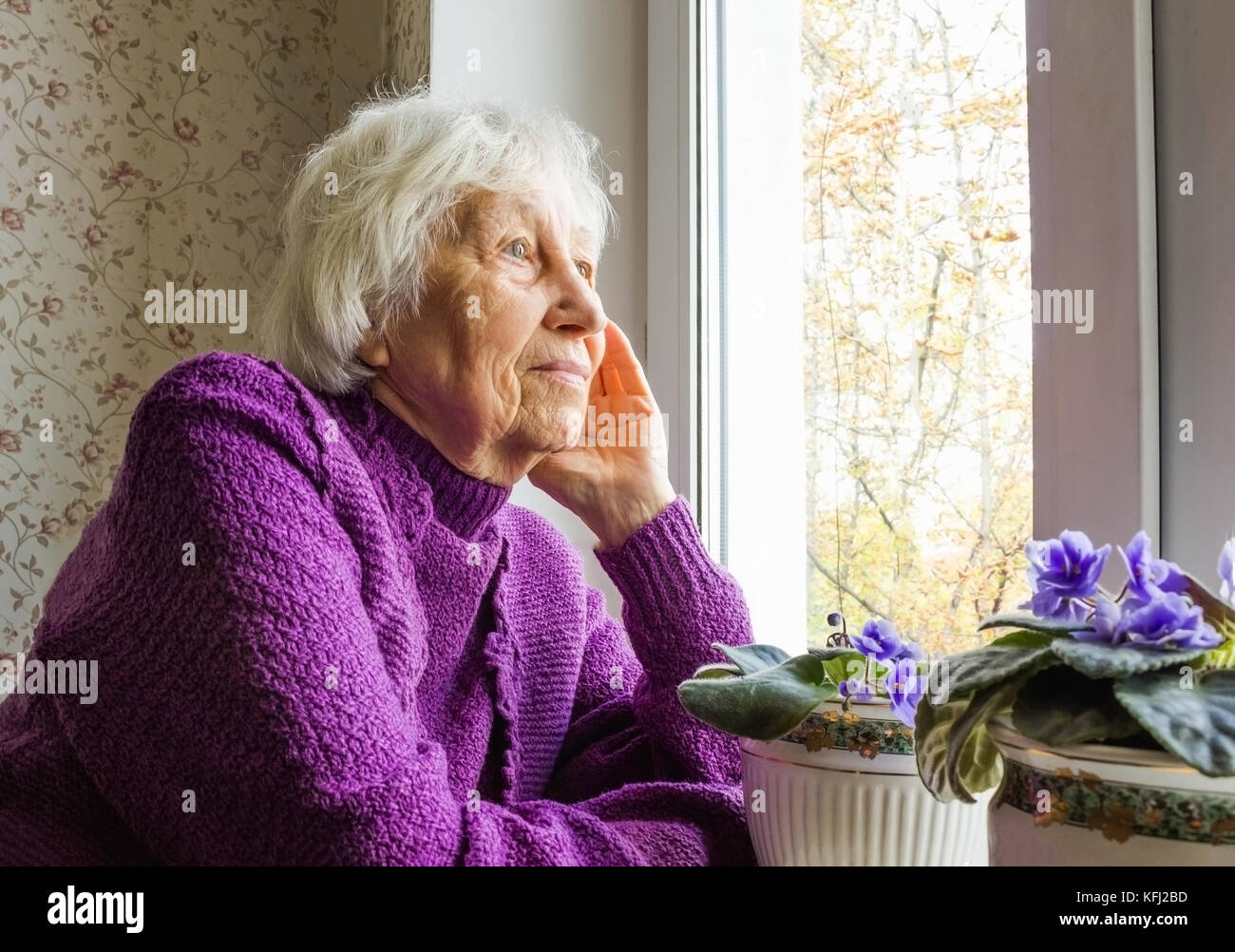 Old lonely woman sitting near the window in his house Stock Photo - Alamy