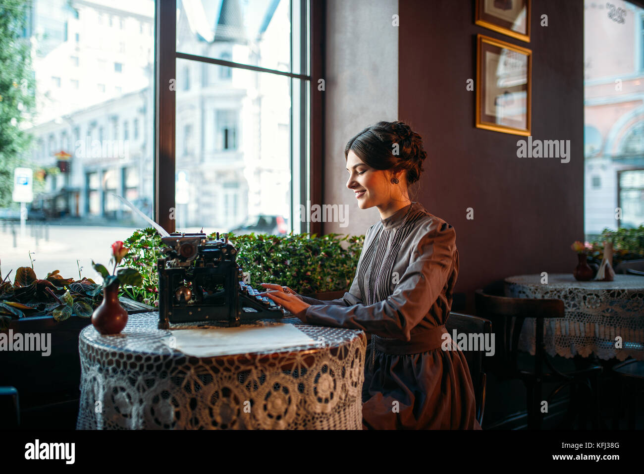Portrait of beautiful young retro lady in cafe with ancient typewriter ...
