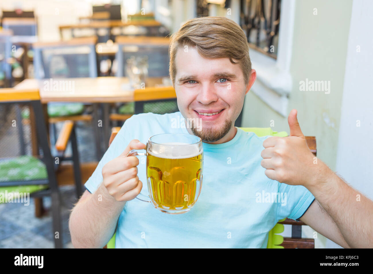 joyful smiling man holding a large beer mug and showing thumbs up ...