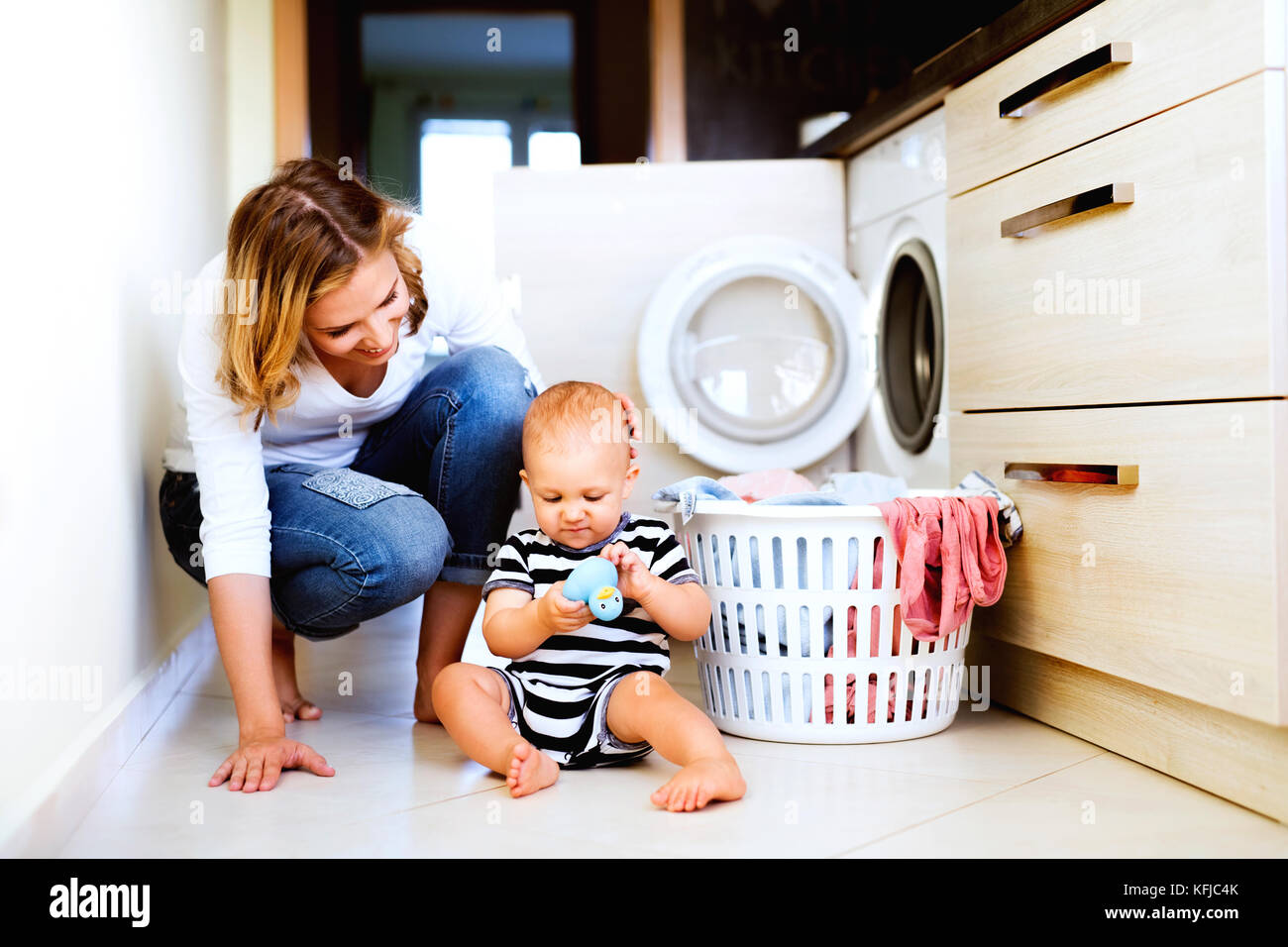 Young mother with a baby boy doing housework Stock Photo - Alamy