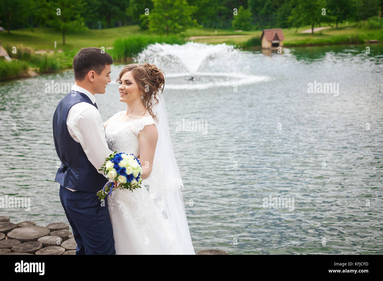 Pretty bride and groom smiling in nature near the lake with fountain Stock Photo - Alamy