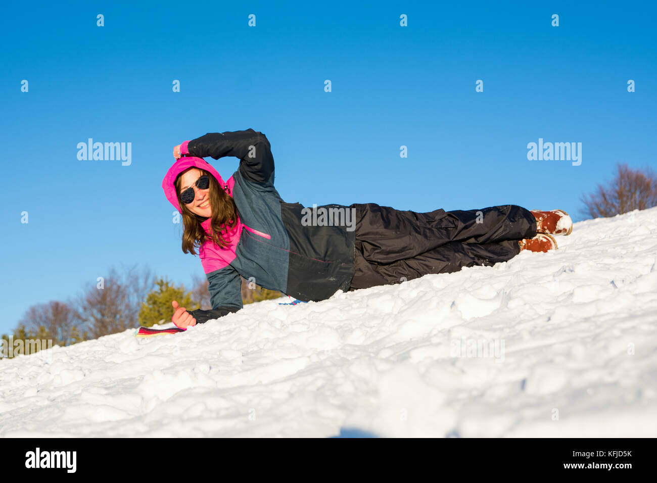 Girl laying on snow covered mountain in ski jacket Stock Photo - Alamy