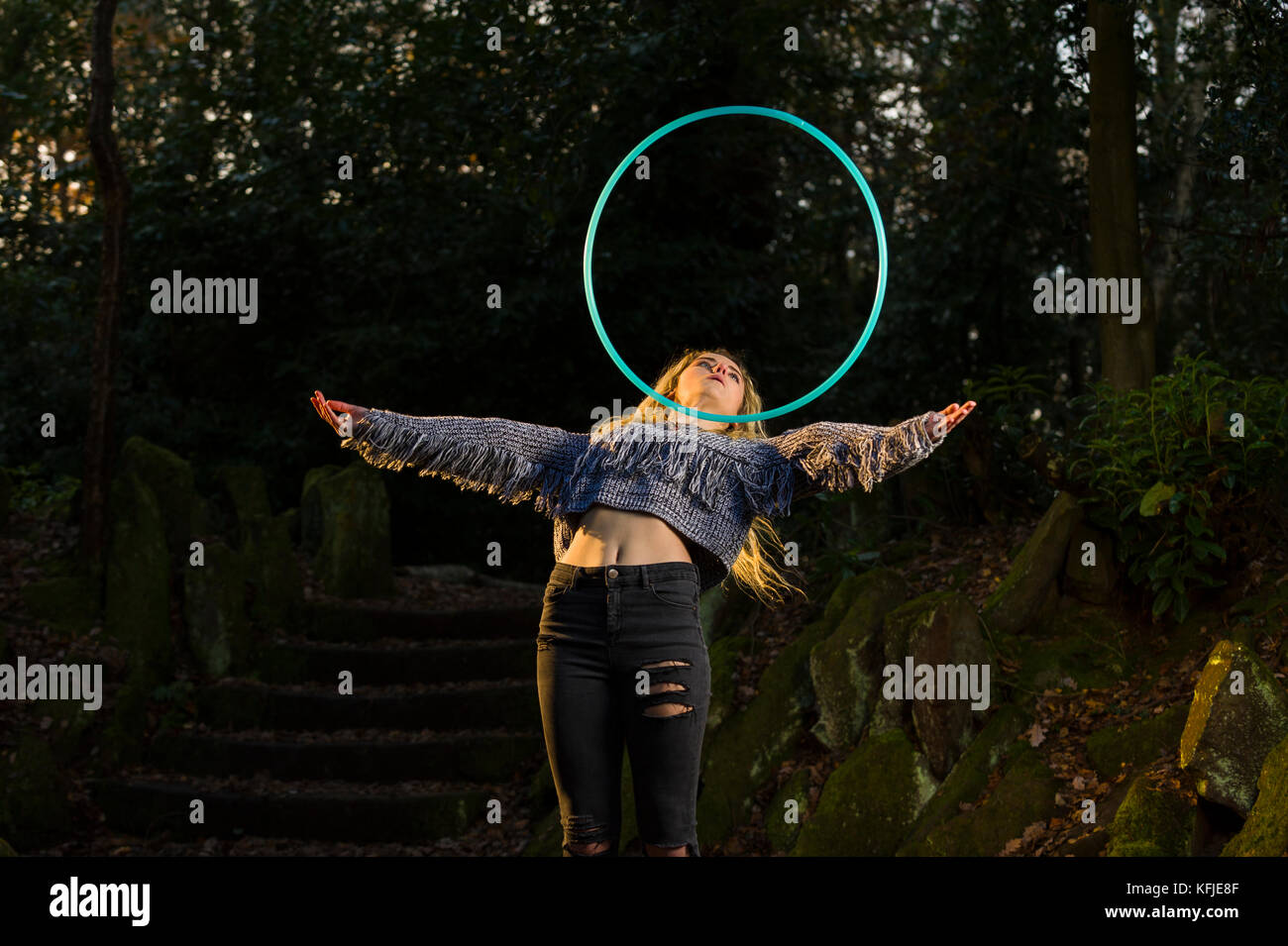 Girl conentrates as she rolls a hoop across her chest, hoop is ...