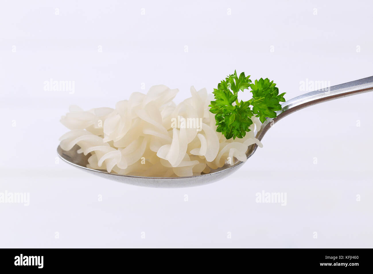 spoon of cooked rice pasta fusilli on white wooden background Stock ...