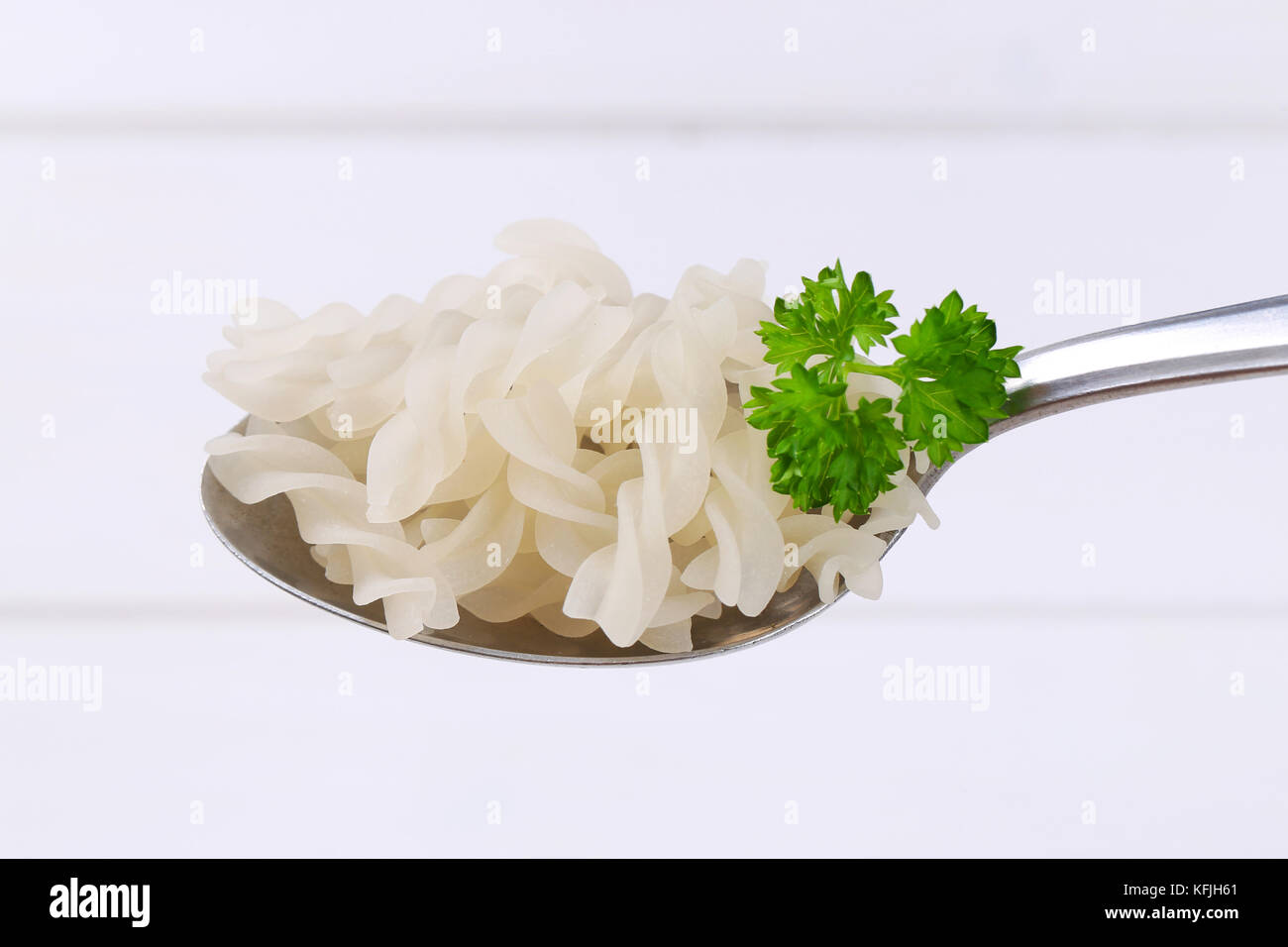 spoon of cooked rice pasta fusilli on white wooden background Stock ...