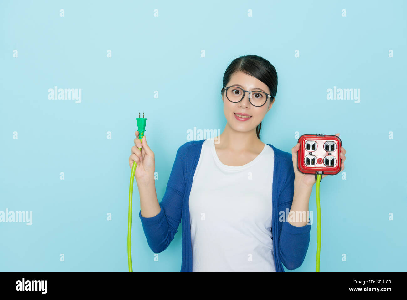 attractive young lady showing plug with socket standing in blue ...