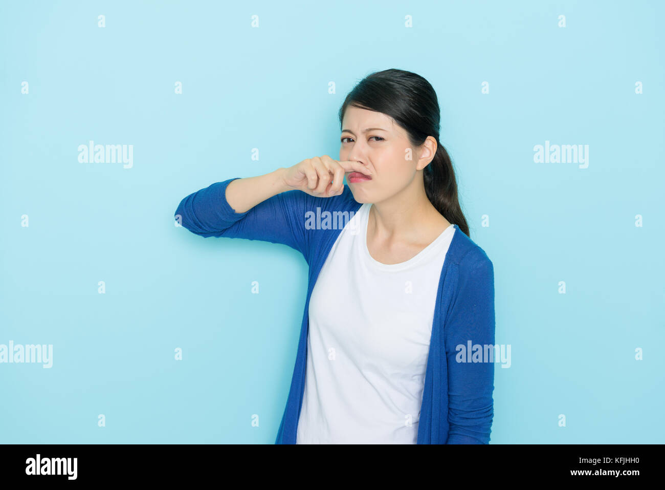 pretty attractive standing in blue background smelling unbearable odor ...