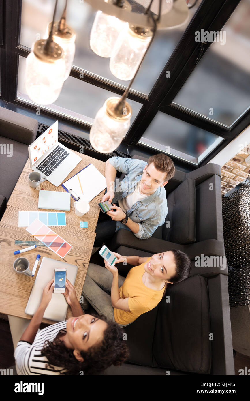 Smiling man and women using their phones while working Stock Photo - Alamy