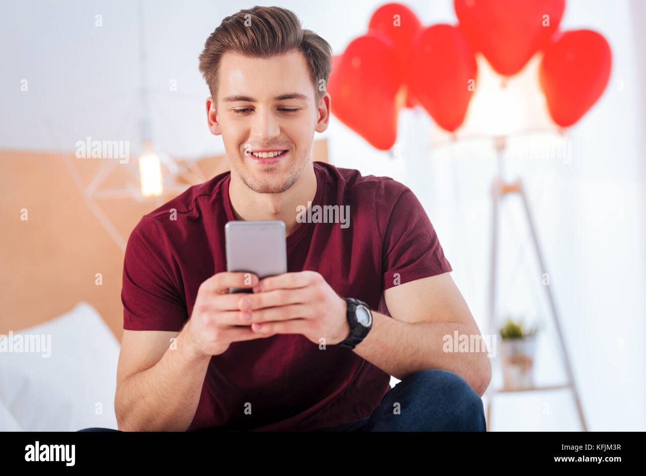 Cheerful young man smiling while writing message Stock Photo - Alamy