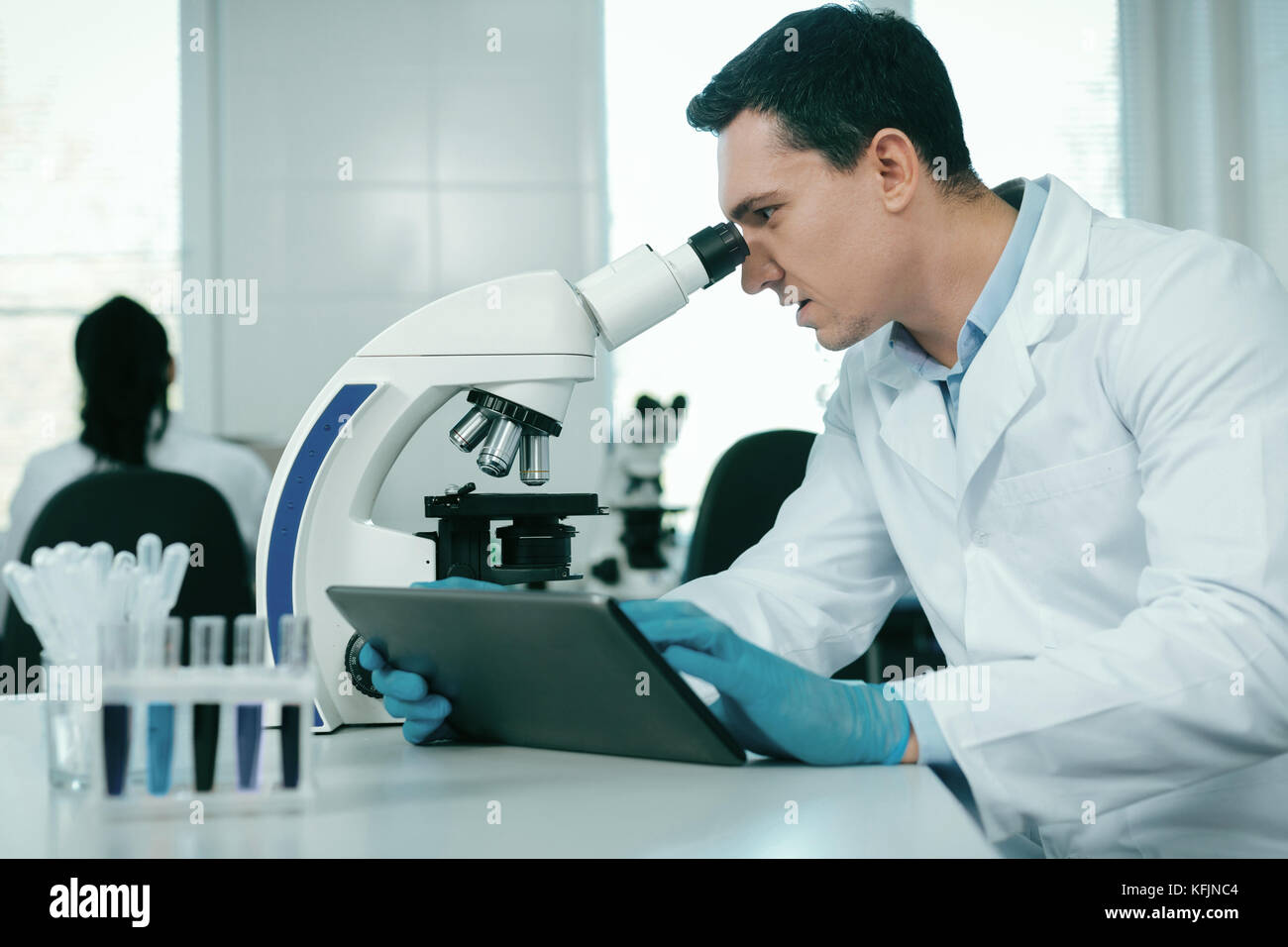 Attentive lab worker sitting in semi position Stock Photo - Alamy