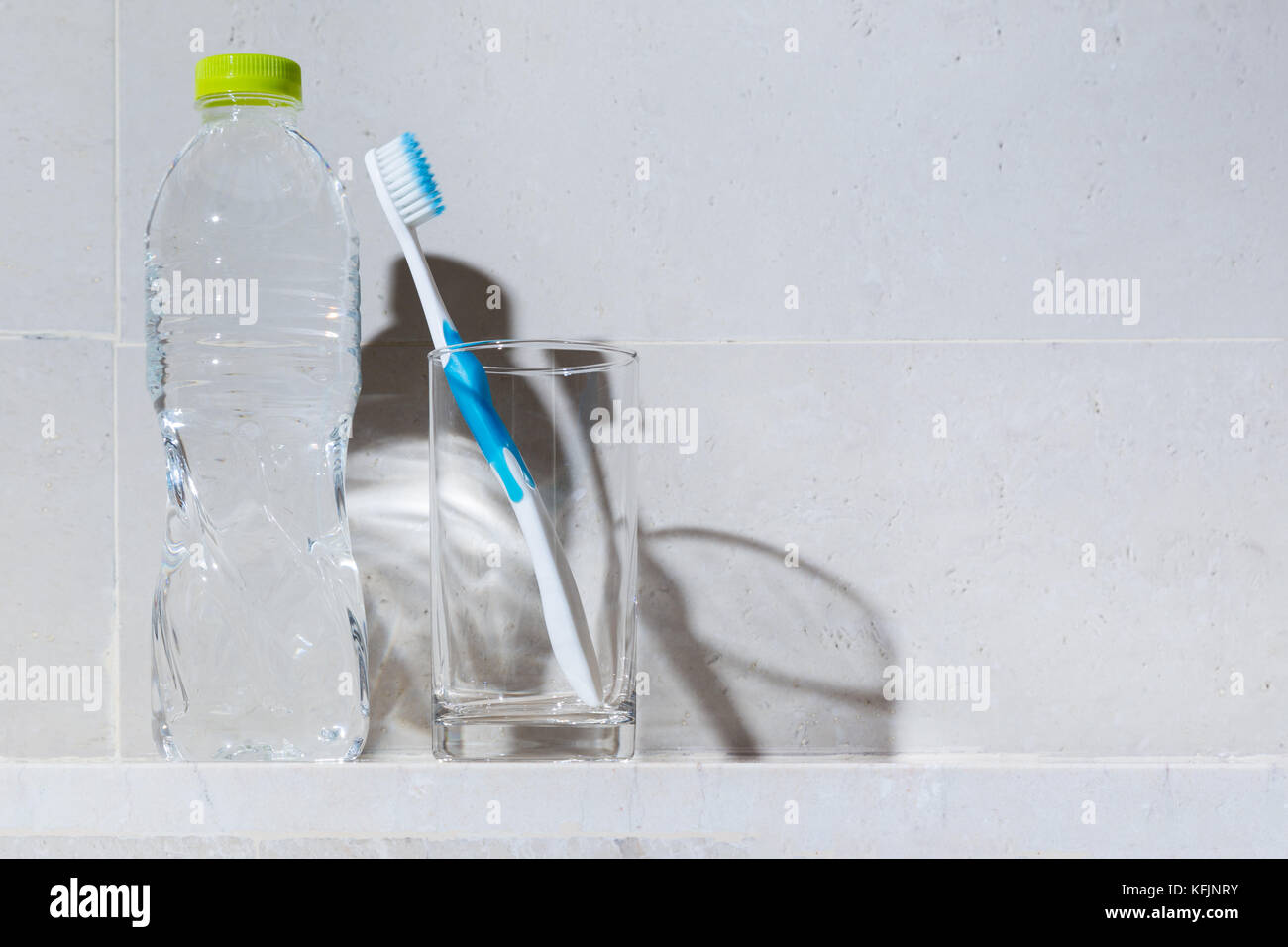 white toothbrush in clear glass cup and full bottle of drinking water ...