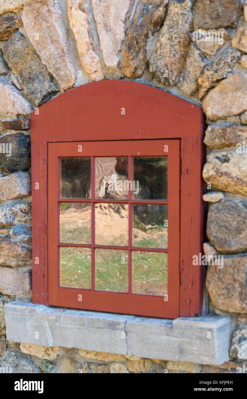 old stone farm building with red framed window with antique distorted ...